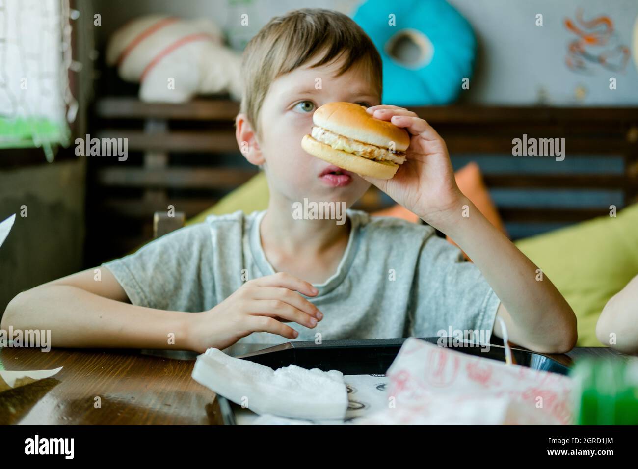 boy eating a big burger with a cutlet. Hamburger in the hands of a ...
