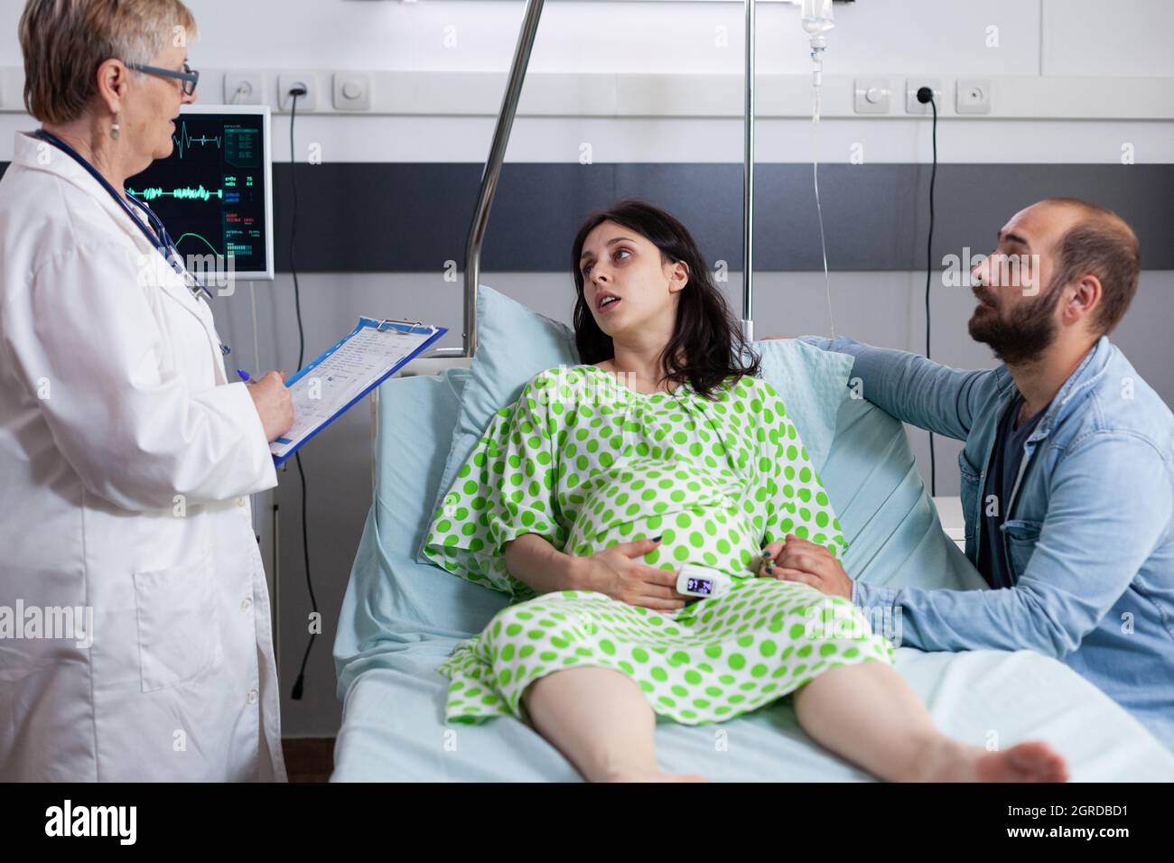 Maternity doctor examining pregnant woman sitting in hospital ward bed ...