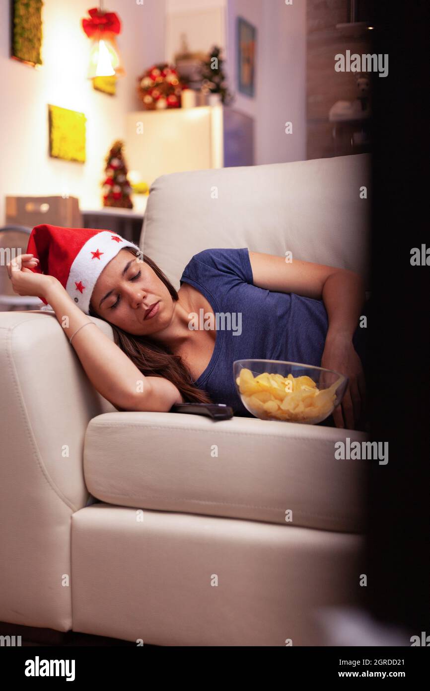 Woman sleeping on couch after watching xmas comedy movie on television ...