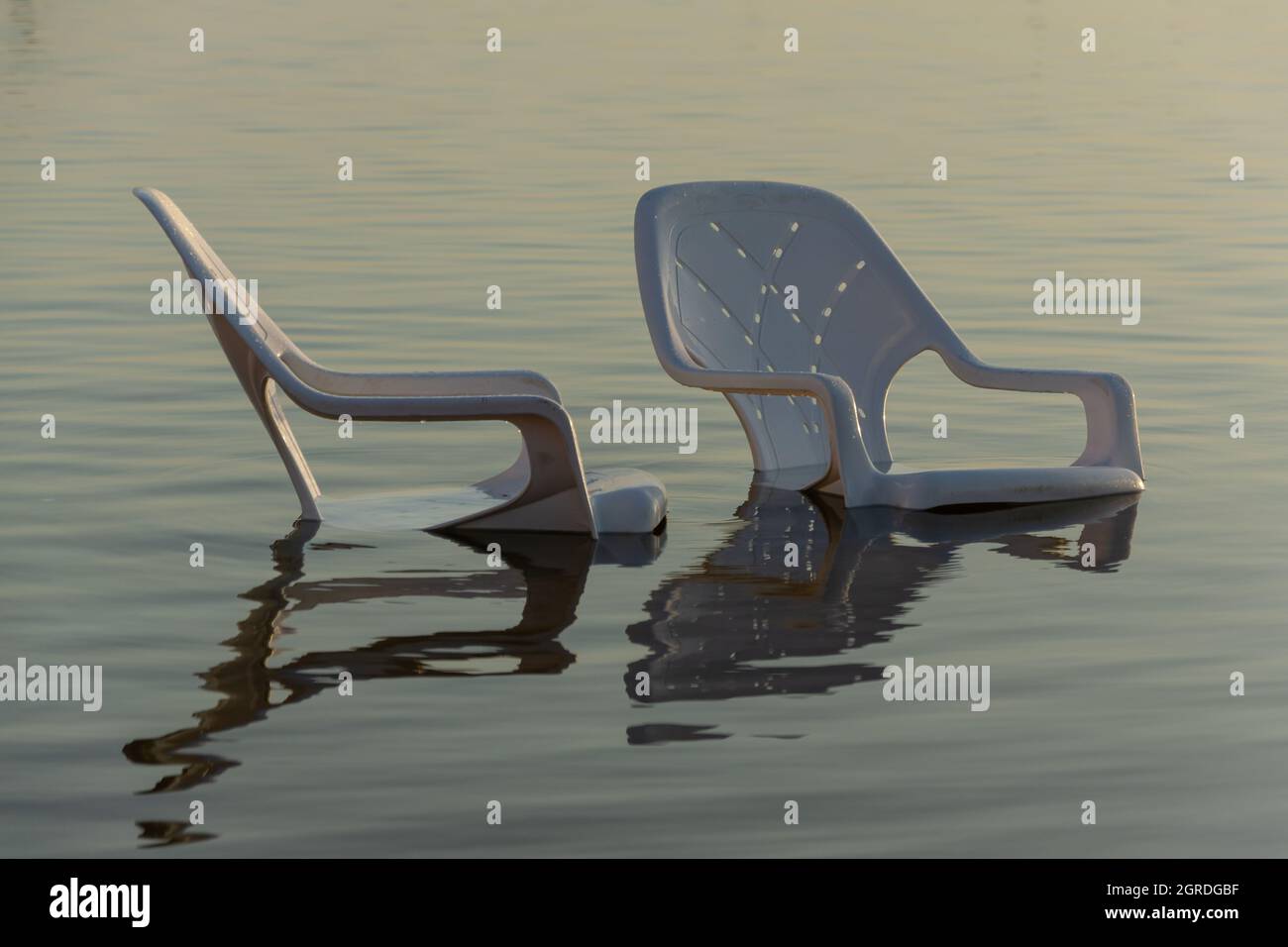 plastic white chairs in the water near the shore on the beach Stock ...