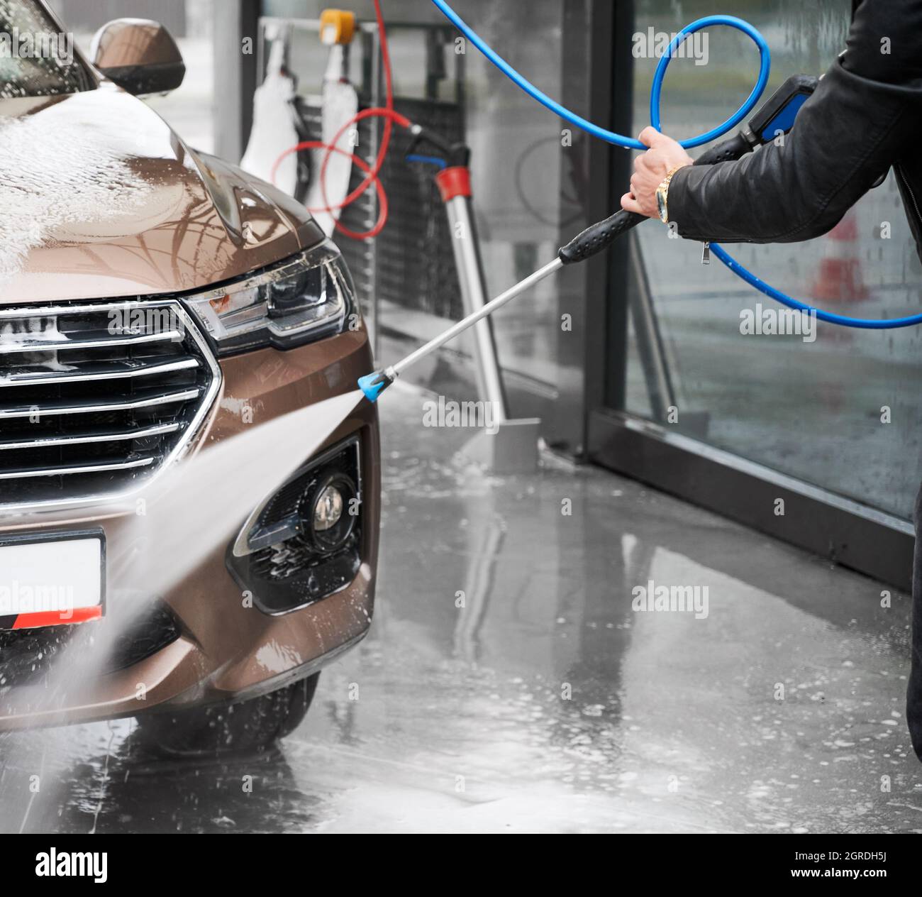 Cropped view of man washing car on carwash station outdoor. Driver ...