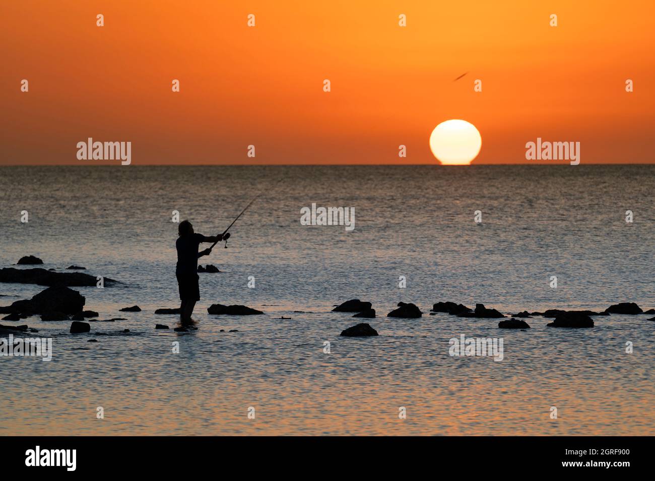 Fisherman casting lure on Alau Beach at sunset, Alau Beach Campground ...