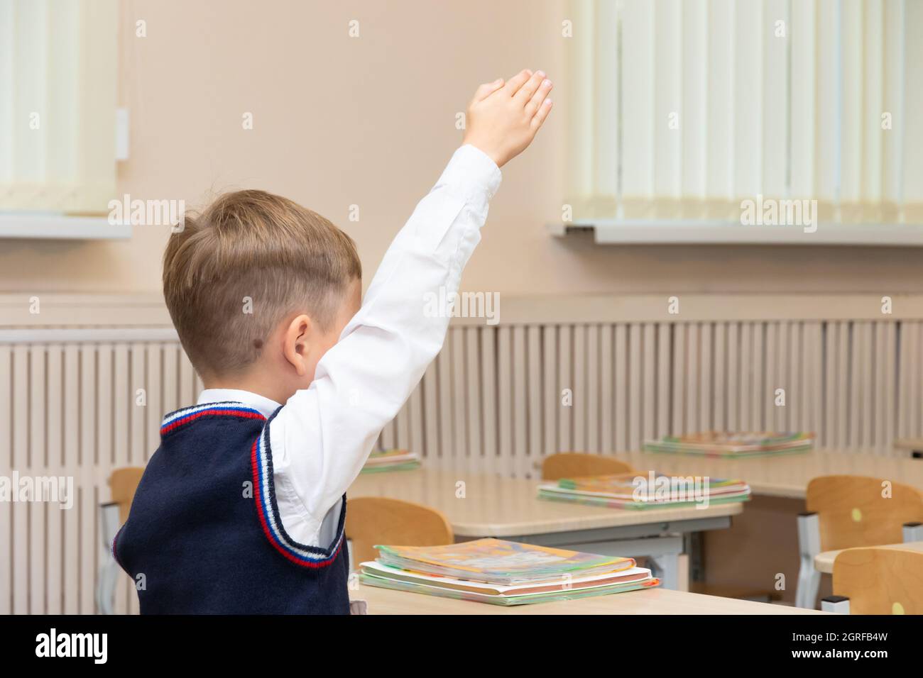 A first-grader boy at a desk with textbooks and notebooks in the ...