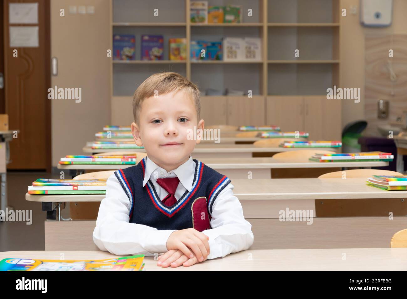 A first-grader boy at a desk with textbooks and notebooks in the ...