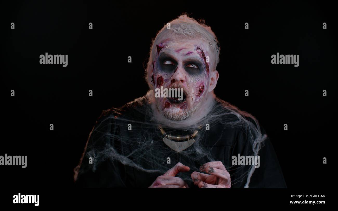 Sinister man with horrible scary Halloween zombie makeup in convulsions ...