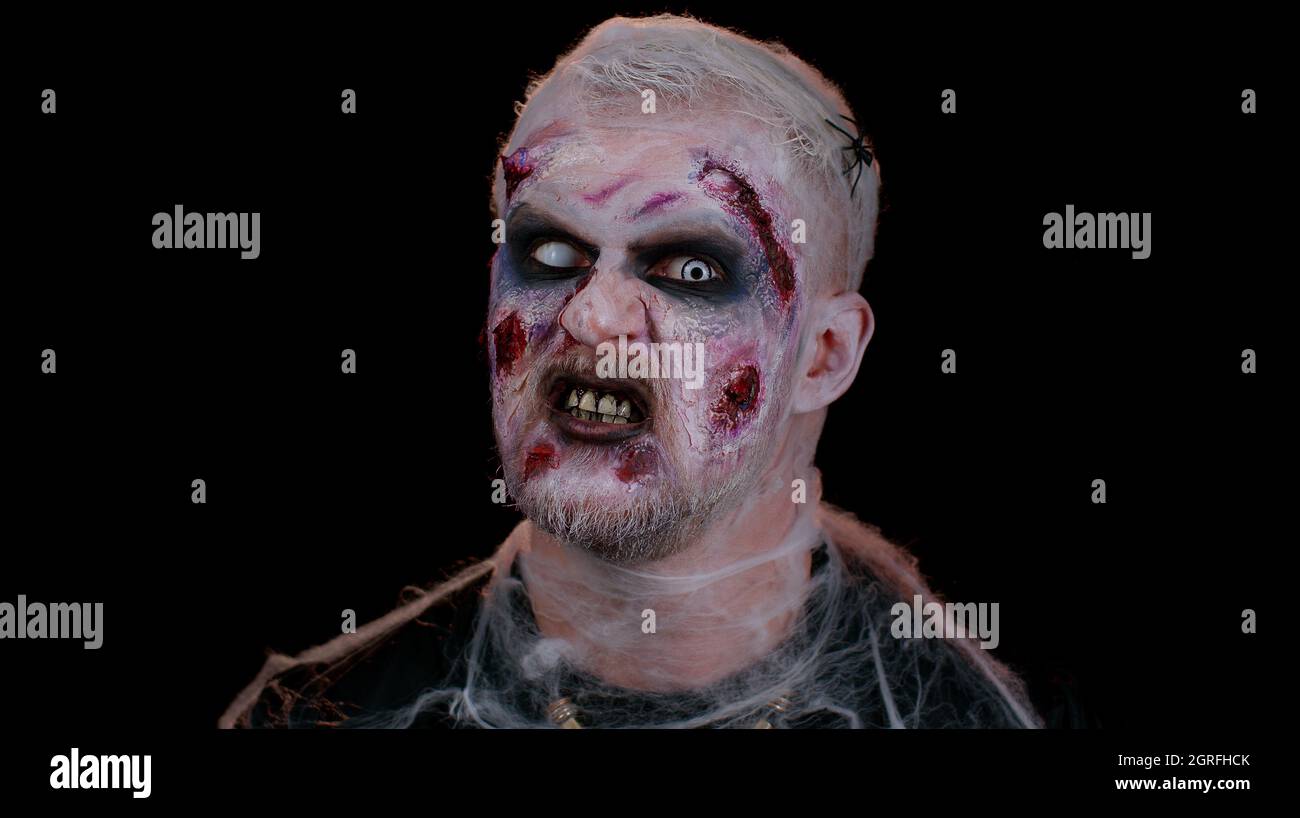 Zombie man with makeup with fake wounds scars and white contact lenses ...