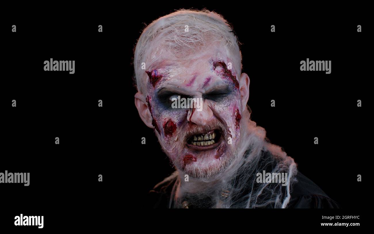 Zombie man with makeup with fake wounds scars looking at camera and ...