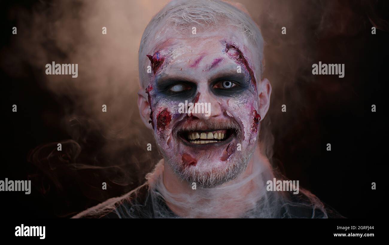 Scary wounded Halloween zombie undead monster man making faces, looks ...