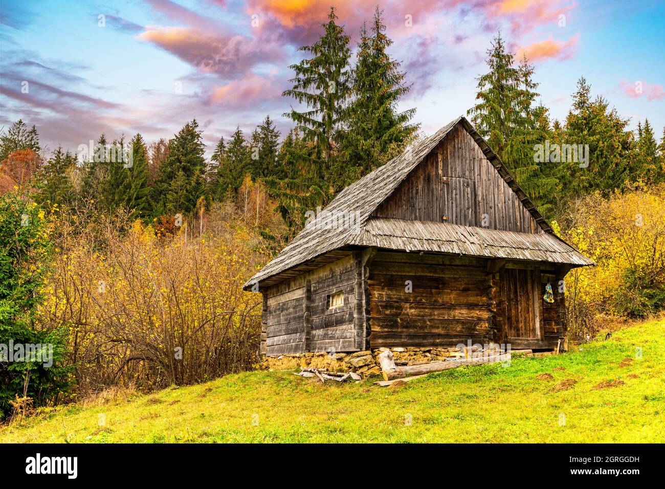 Old house in a small valley with green meadows and colorful forests ...