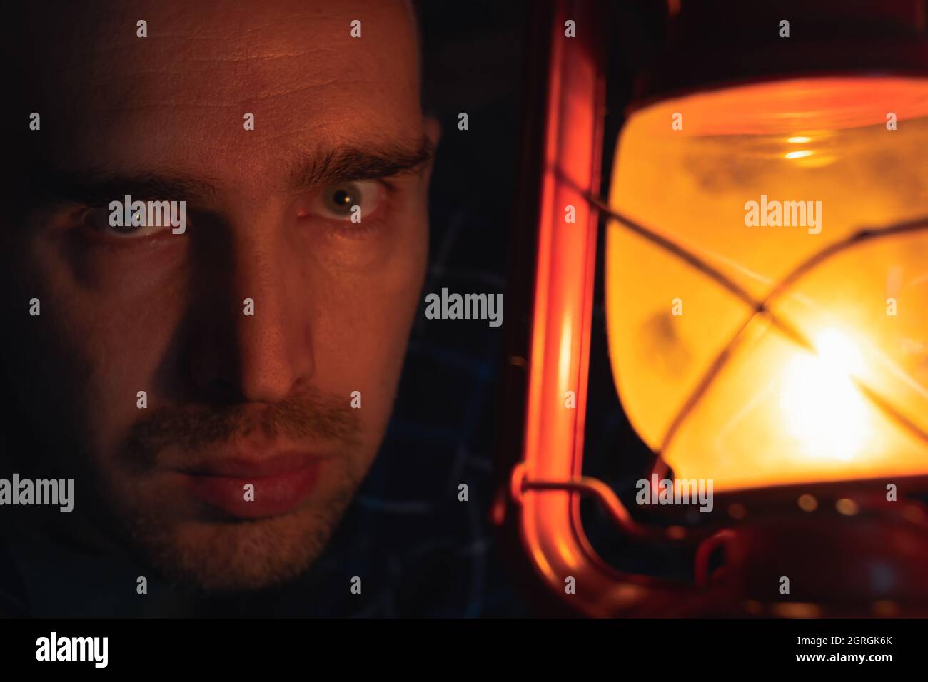 Close-up of a man's face in the light of a kerosene lamp. Part of the ...