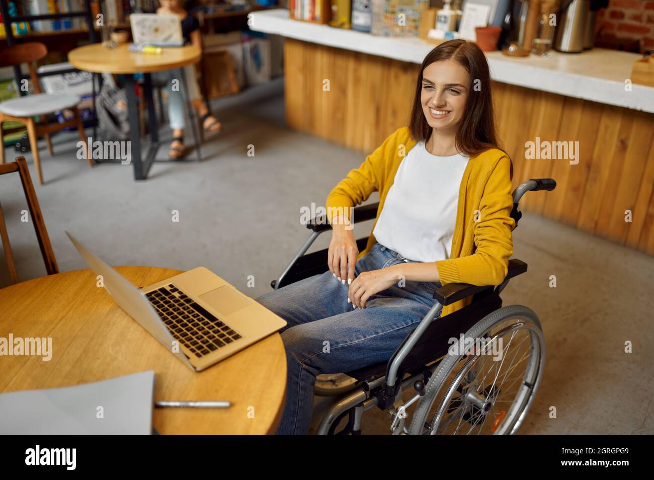 Disabled female student in wheelchair using laptop Stock Photo - Alamy
