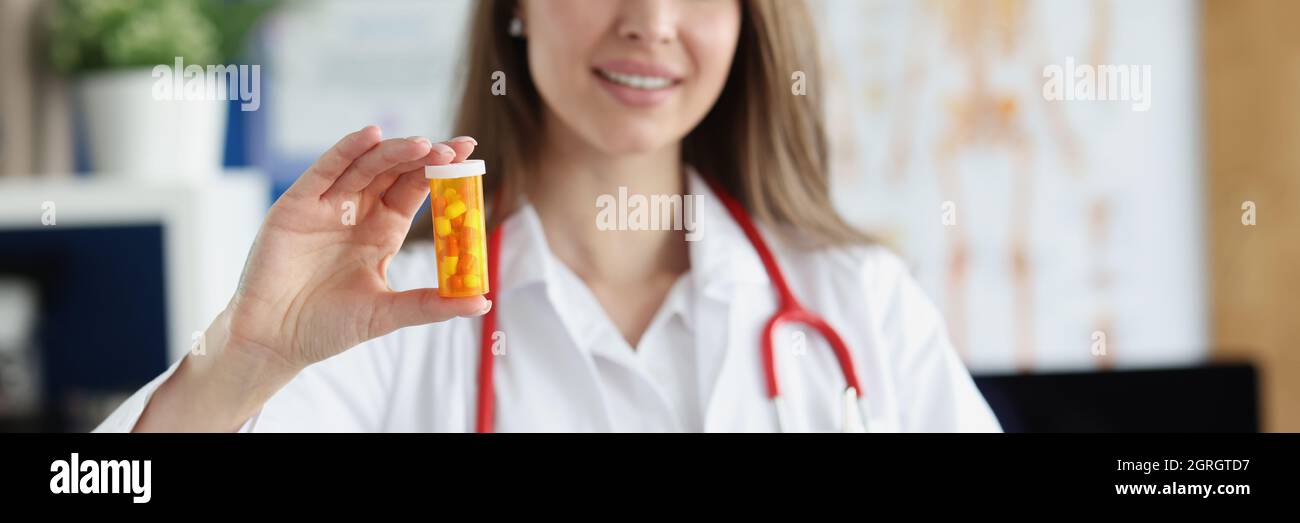 Smiling family medicine doctor holds and gives patient jar of pills ...