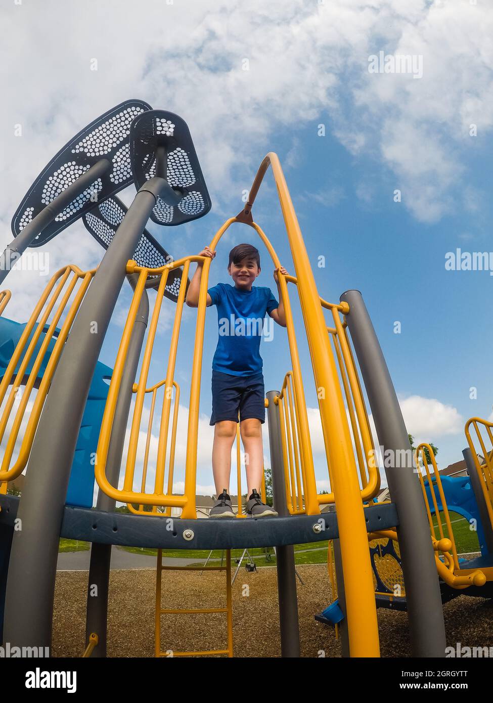 Low angle view of boy standing at the top of a climber at playground ...