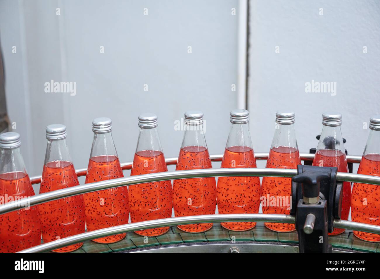 Glass bottled red juice on steel conveyor of production line in ...