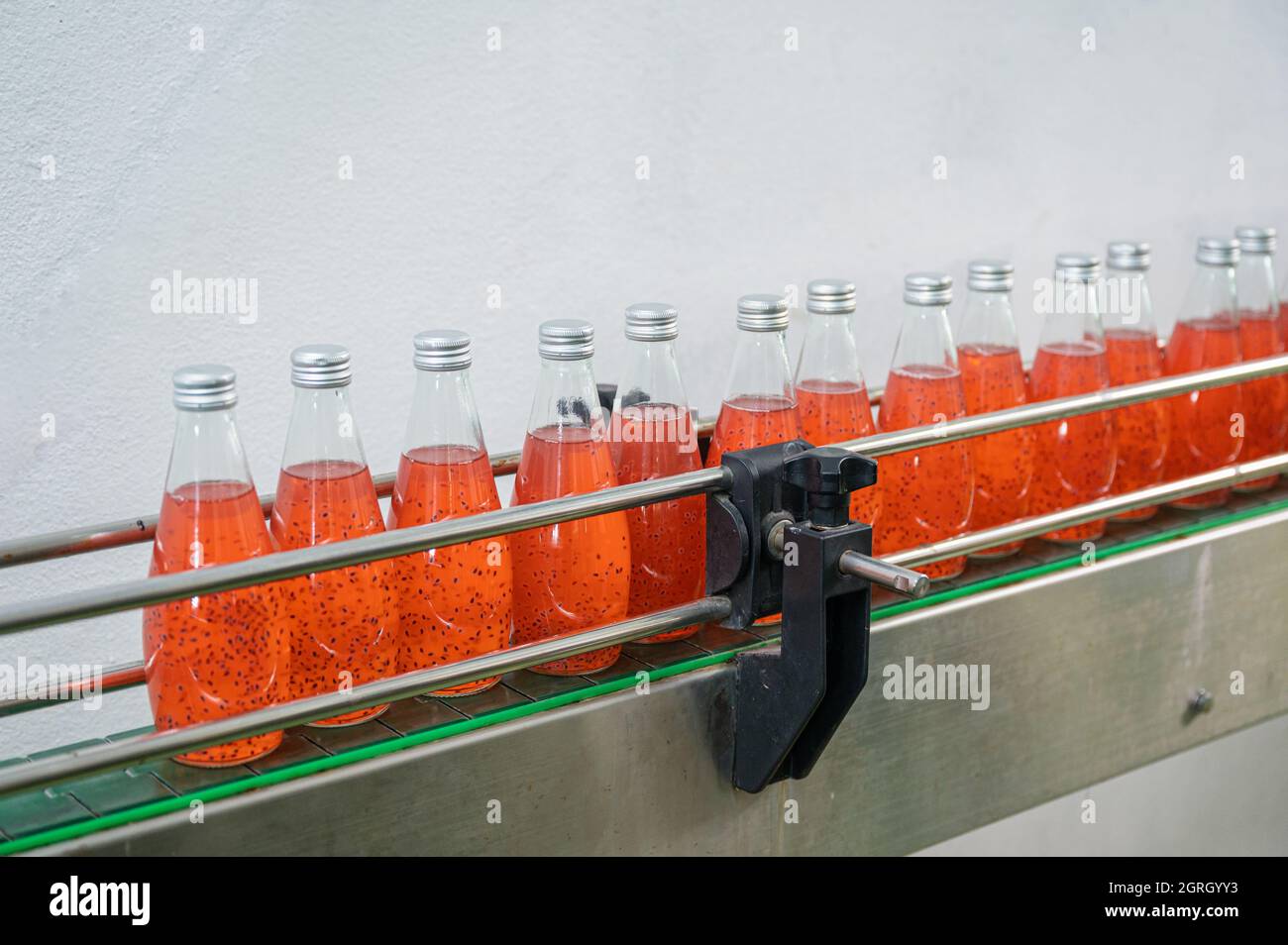 Glass bottled red juice on steel conveyor of production line in ...