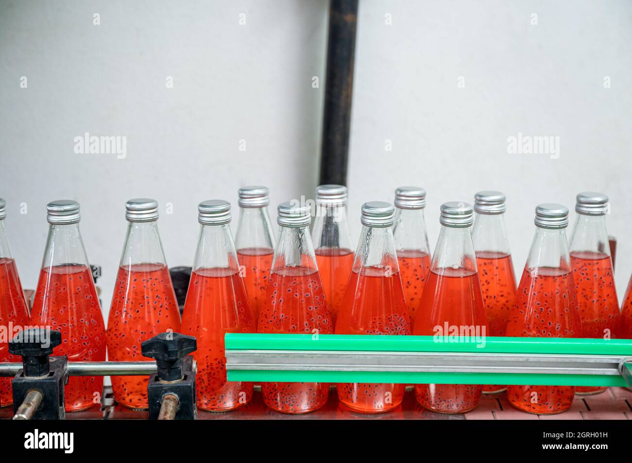 Glass bottled red juice on steel conveyor of production line in ...