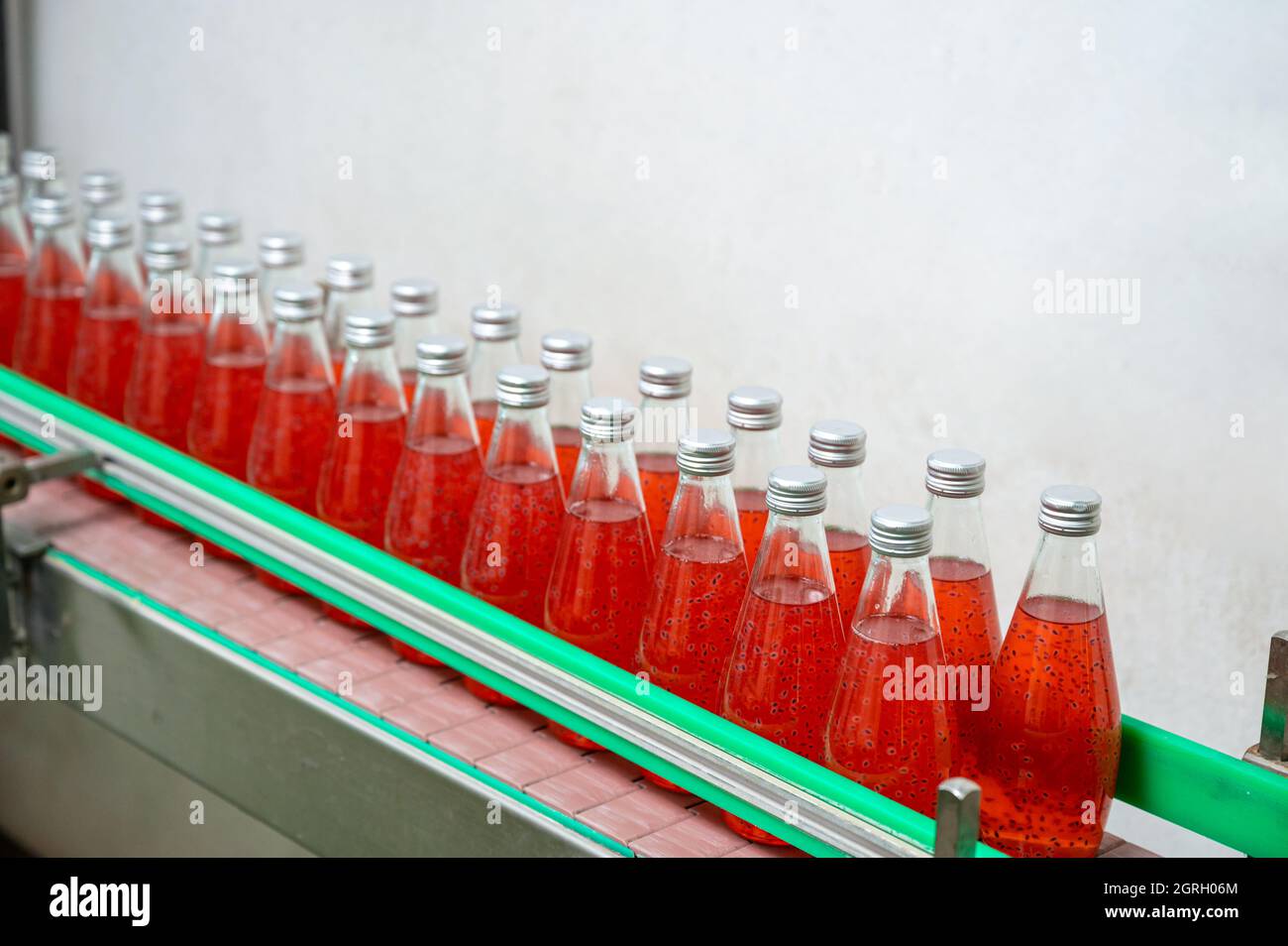 Glass bottled red juice on steel conveyor of production line in ...