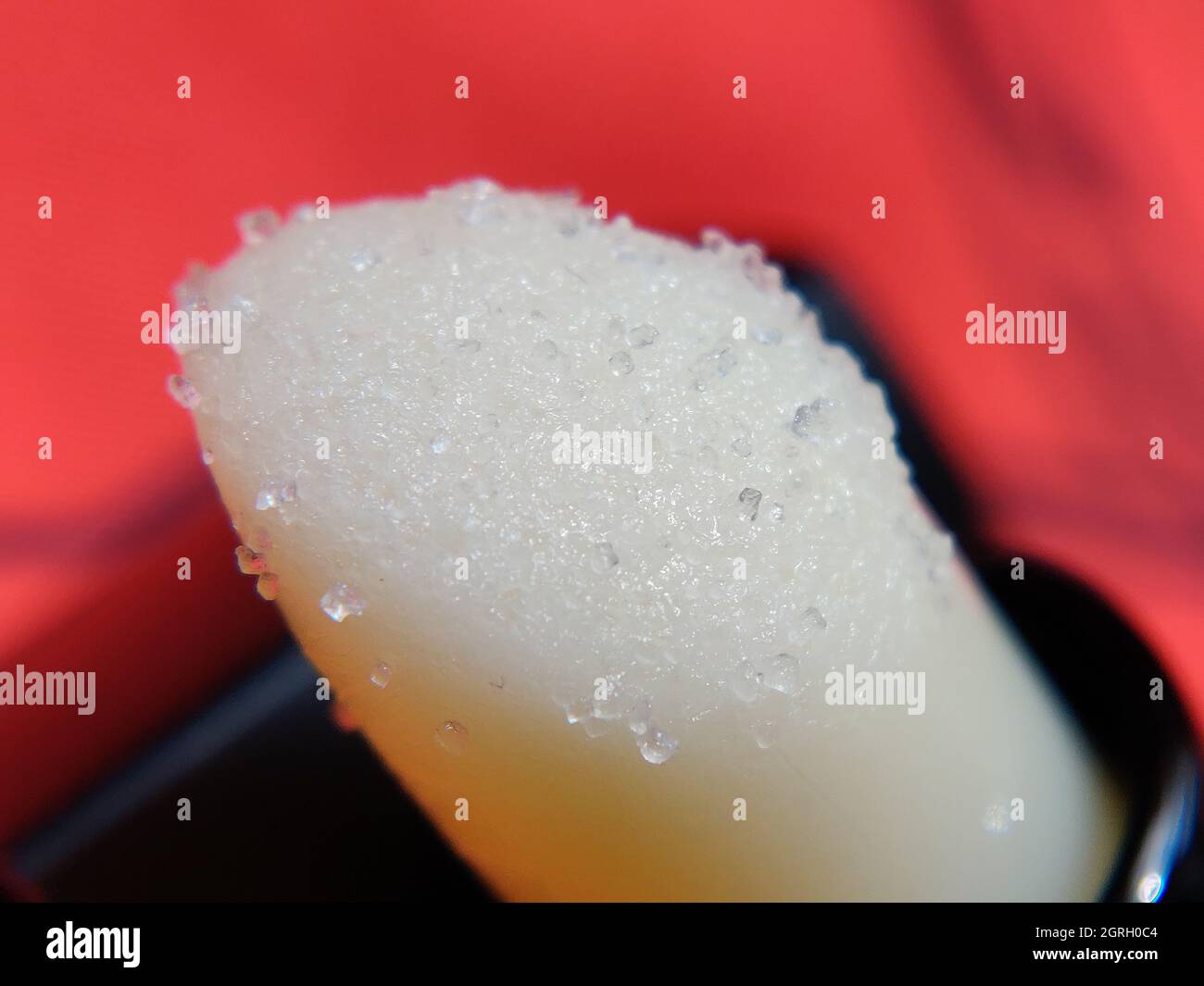 Macro photo of white sugar lip scrub on red background Stock Photo - Alamy