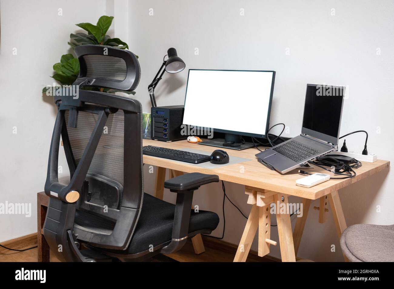 Wooden desk setting with laptop, display, mouse, lamp, ergonomic chair ...