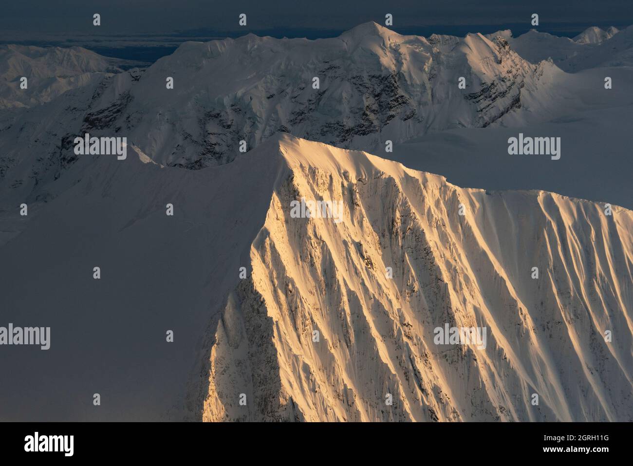 Sunset shines on snow covered peaks seen aerially in the Alaska Range ...