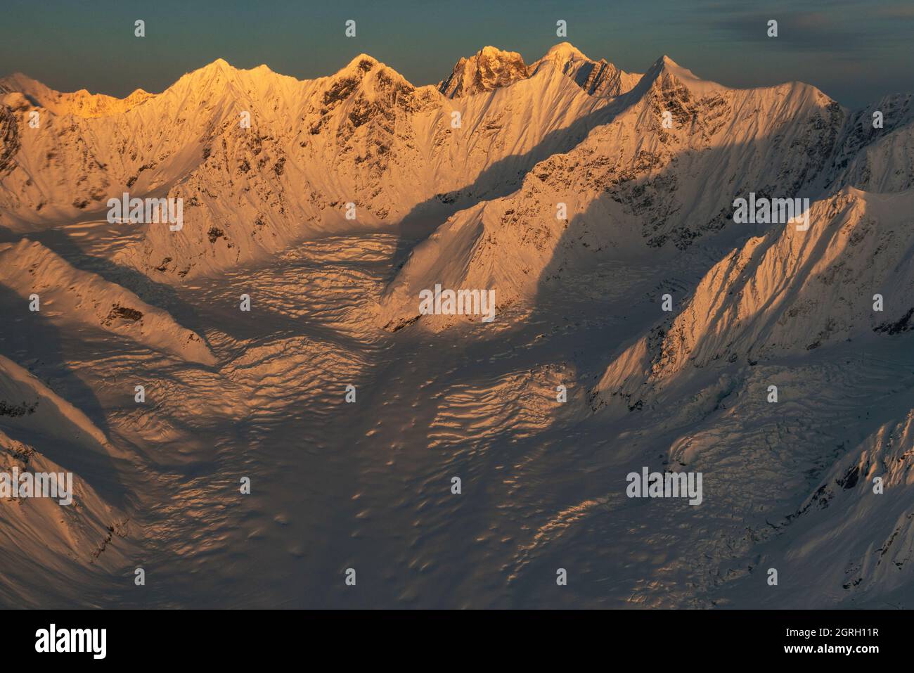 Sunset shines on snow covered peaks seen aerially in the Alaska Range ...