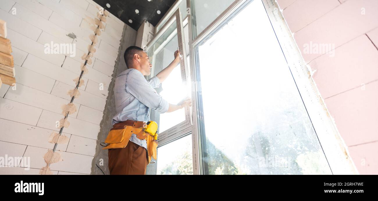 Construction worker installing window in house Stock Photo - Alamy