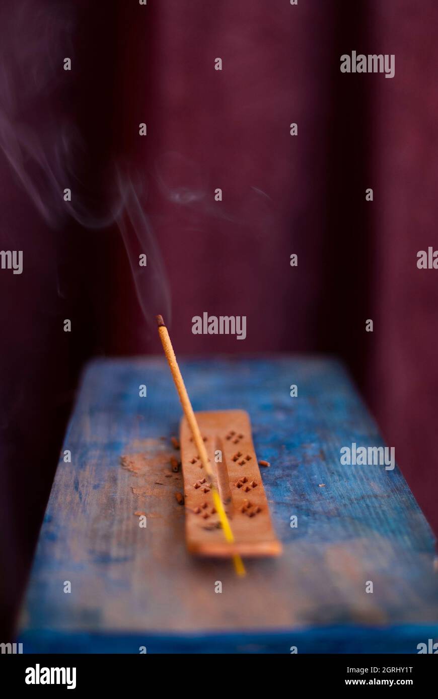 incense stick lit with smoke thread with dark background on sky blue ...