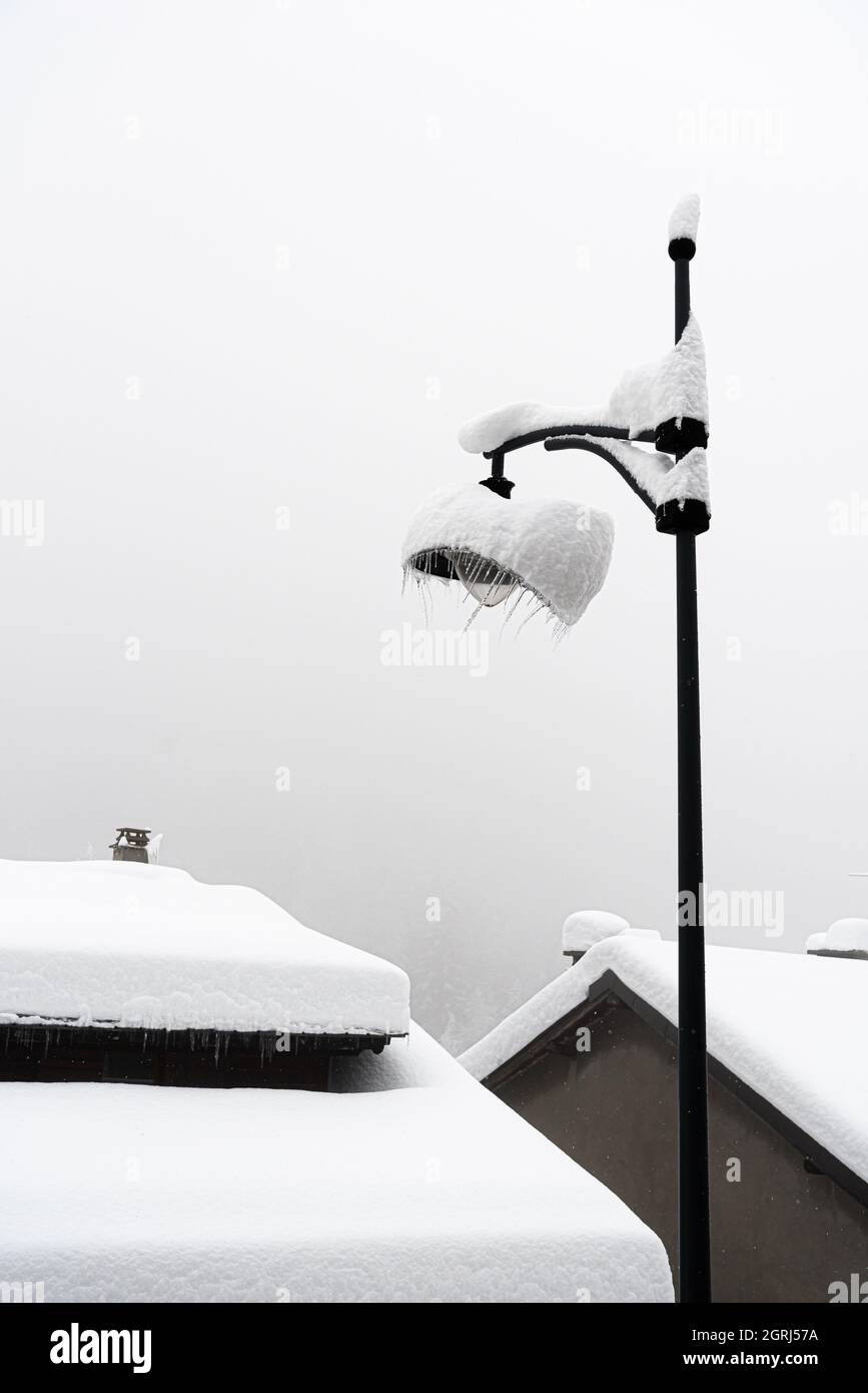 Lamp post in alpine village covered in fresh snow with icicles bent by ...