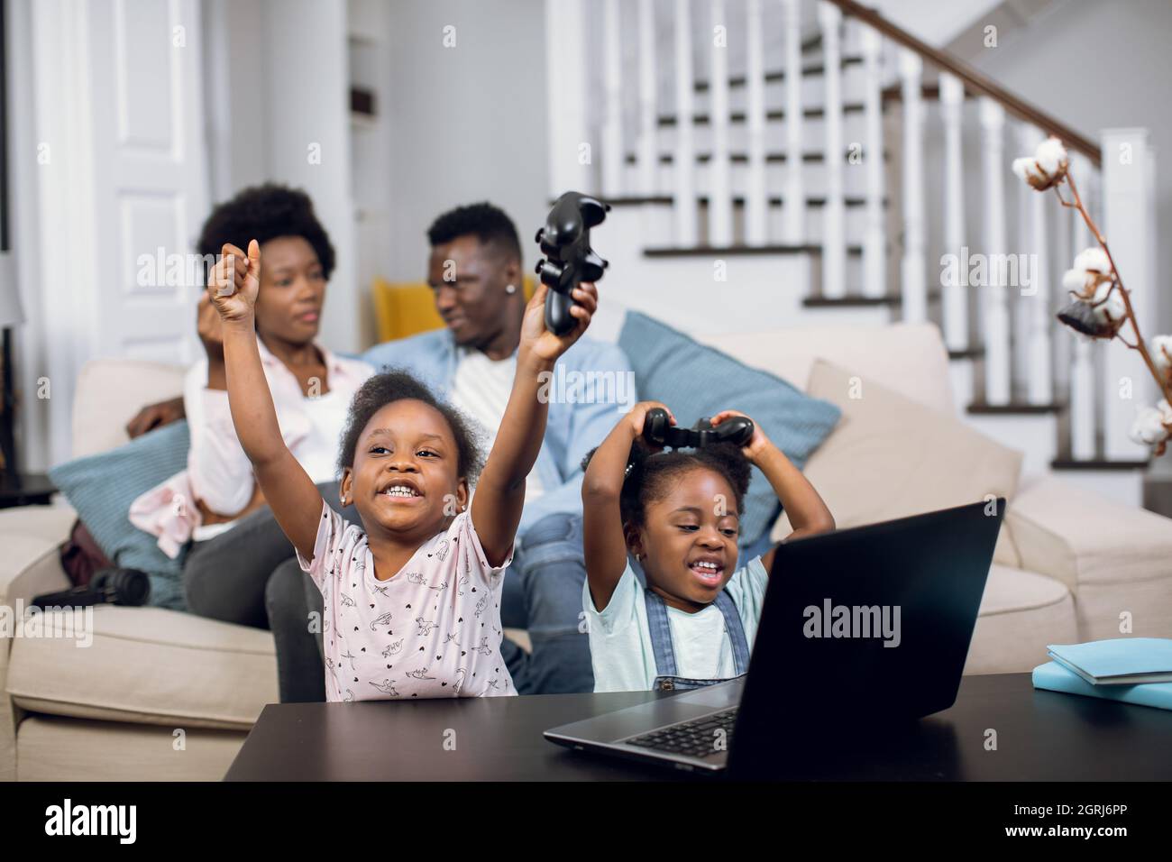 Cheerful african sisters playing video games on laptop with wireless ...