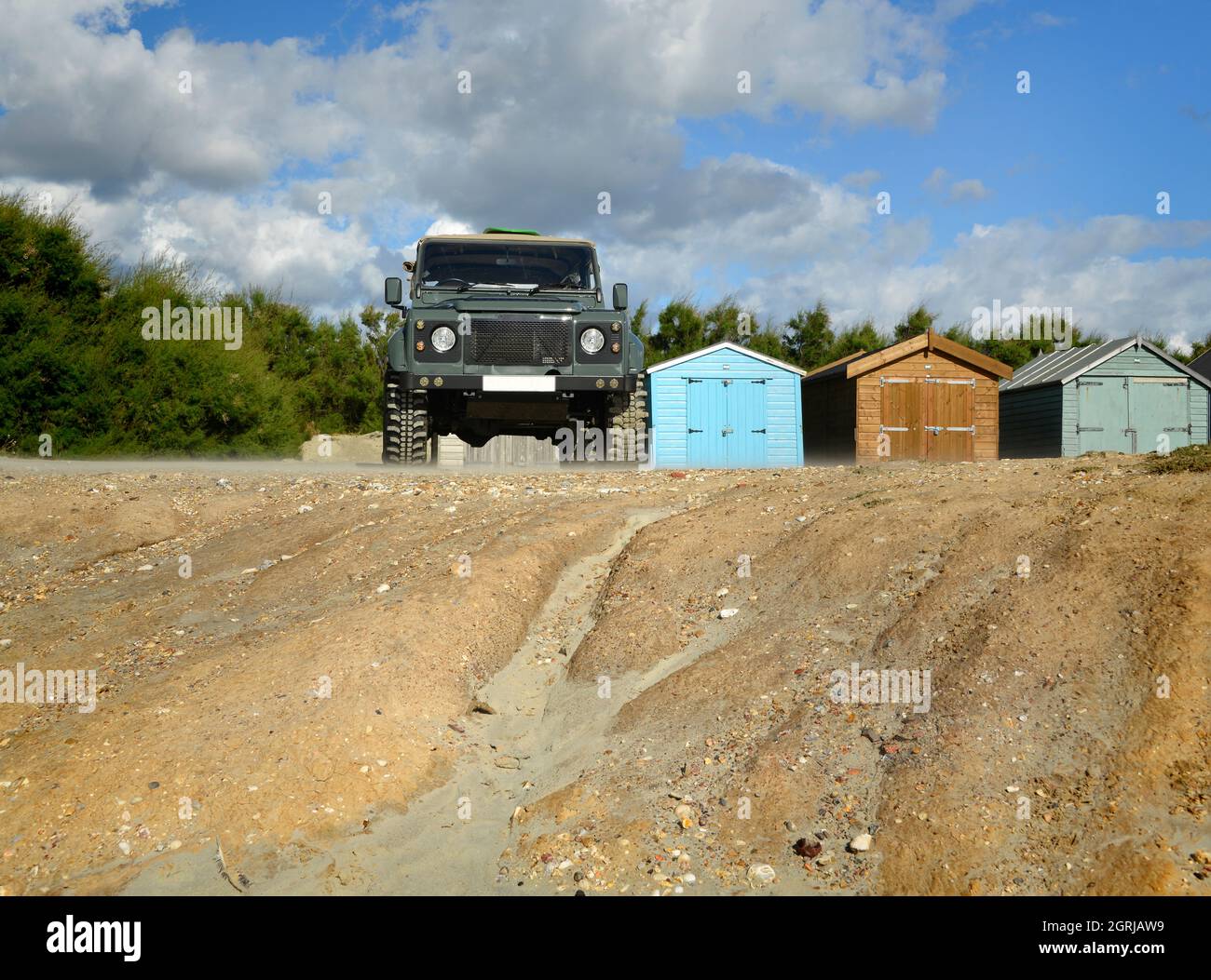 4 wheeled drive jeep parked on the beach above a slope with beach huts ...