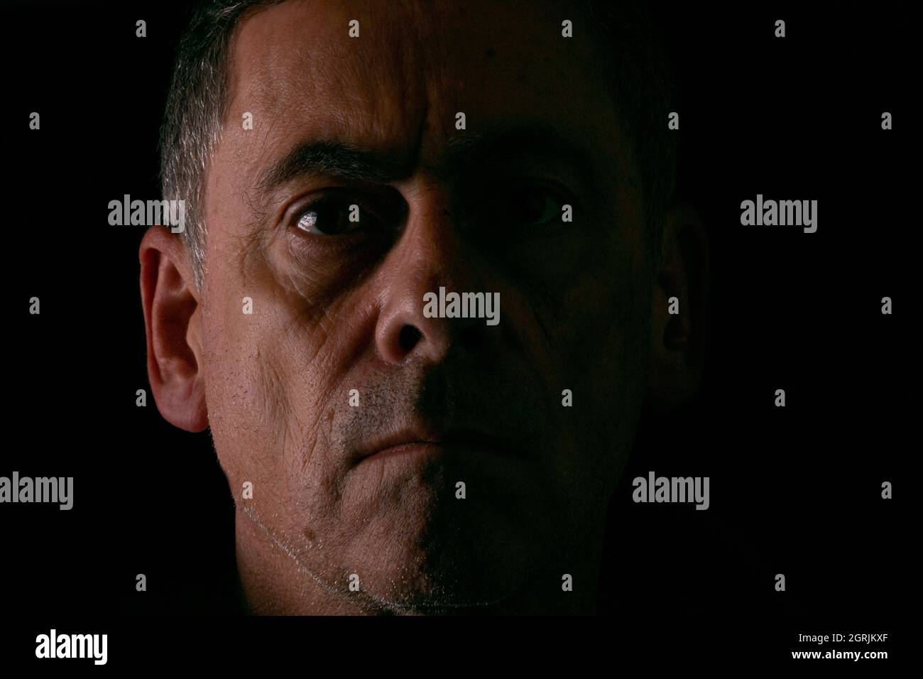 Portrait of illuminated senior man half of his face with black ...