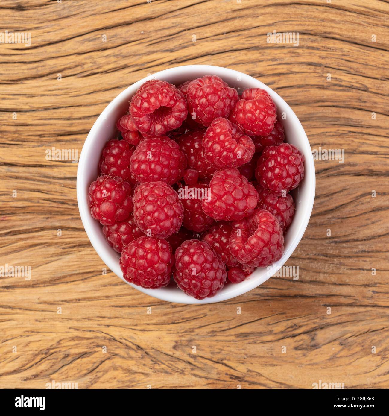 Raspberries in a bowl over wooden table Stock Photo - Alamy