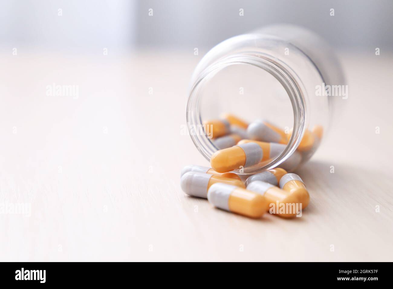 Pills on a light wooden table, medication in capsules scattered from a ...