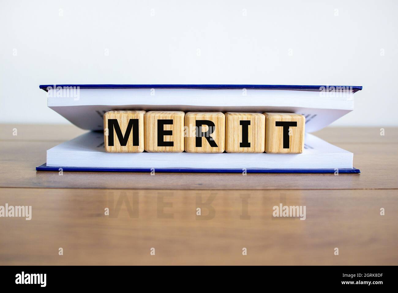 Merit symbol. The concept word 'merit' on wooden cubes between pages of ...