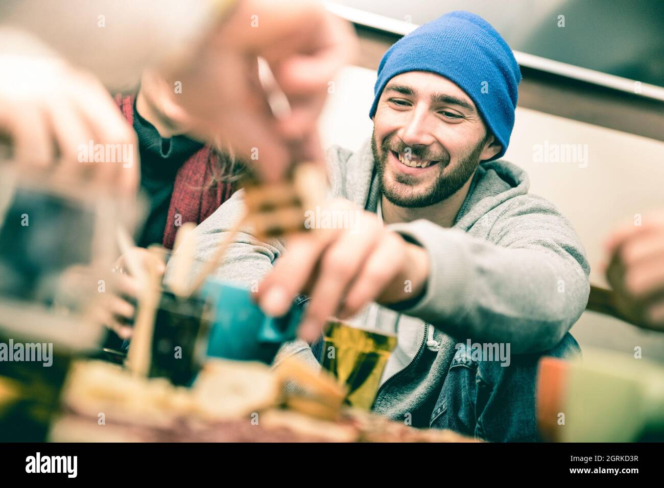 Happy guy with friends eating finger food and drinking beer at pub ...
