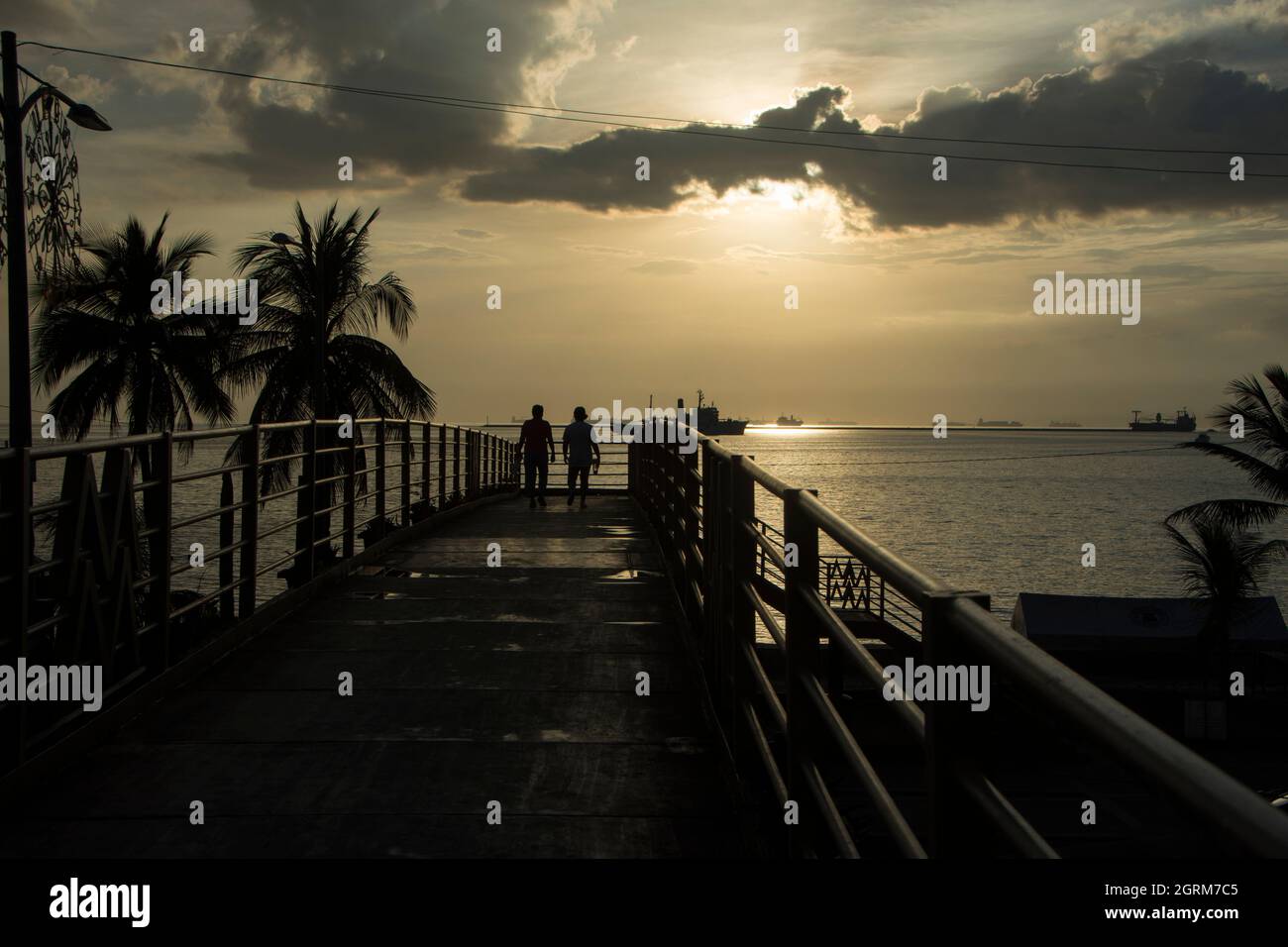 Two people crossing the Roxas Boulevard on a pedestrian bridge towards ...