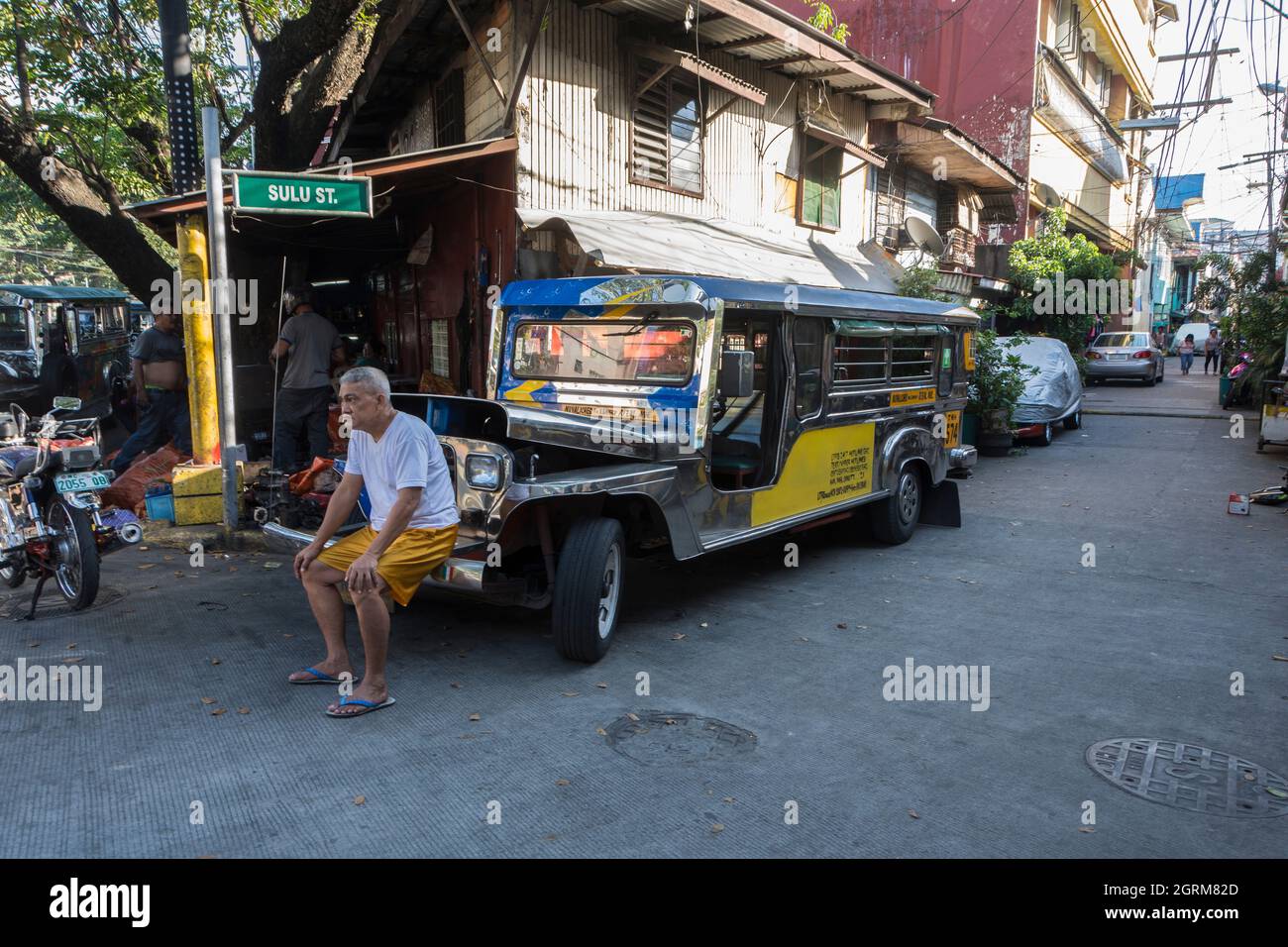 Man sits on the bumper of a jeepney in a street in Manila,Philippines ...