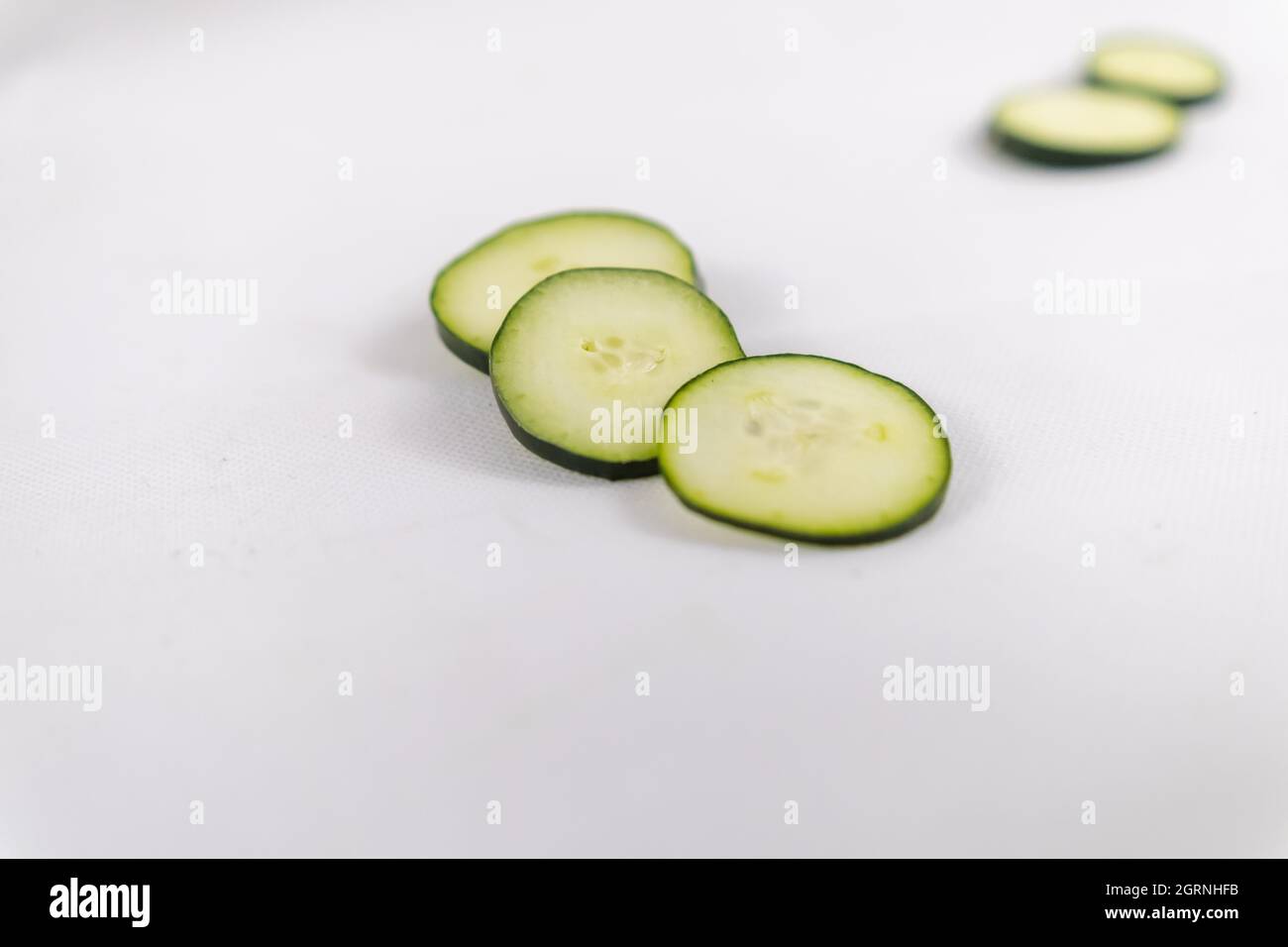 Fresh cucumber slices scattered on a white surface Stock Photo - Alamy