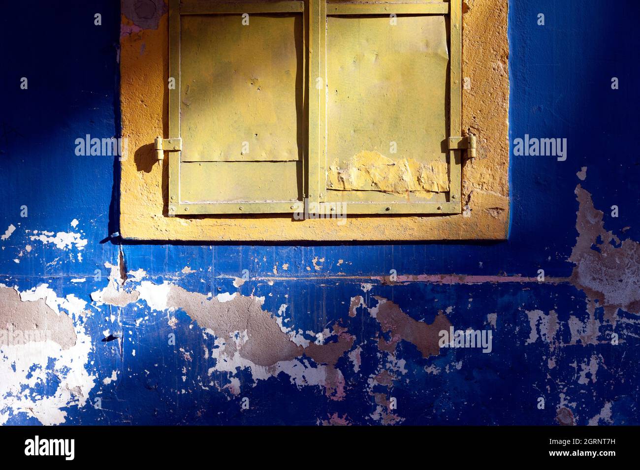 Closed old yellow window, shutter, yellow window in the old blue wall ...