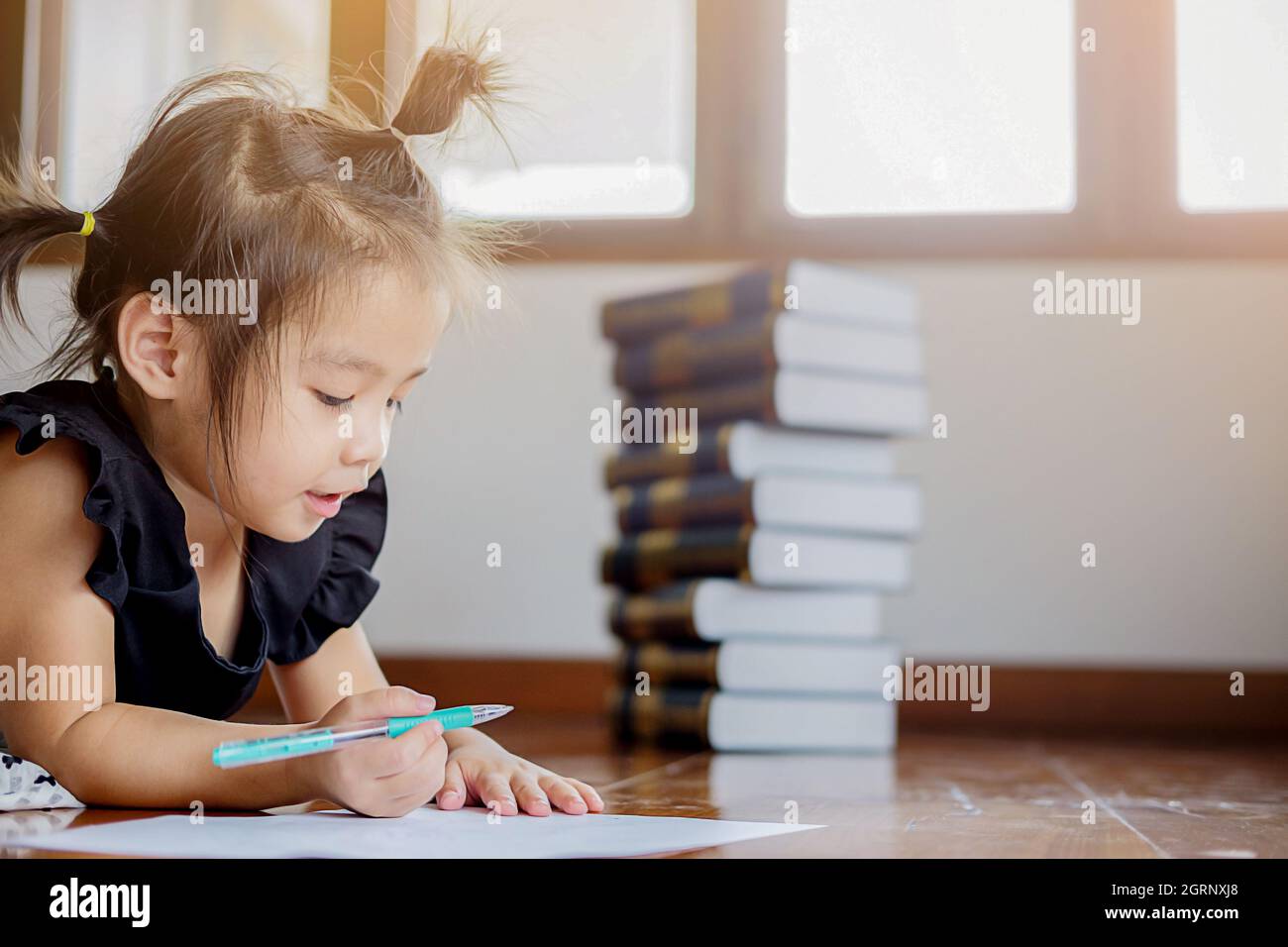 Cute Baby Girl Writing While Lying On Floor At Home Stock Photo - Alamy