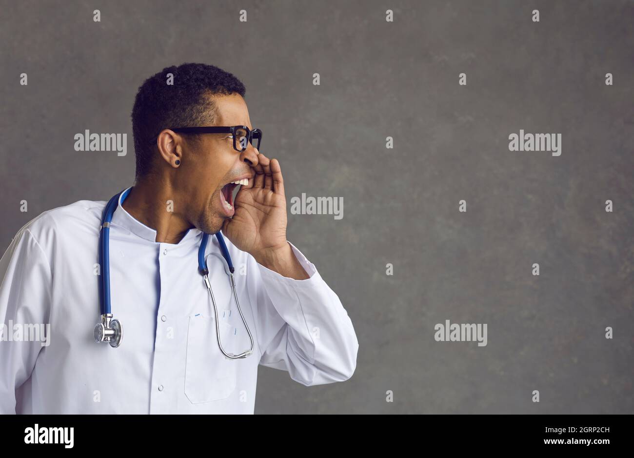 Young afro american doctor shouting screaming loudly looking aside to ...