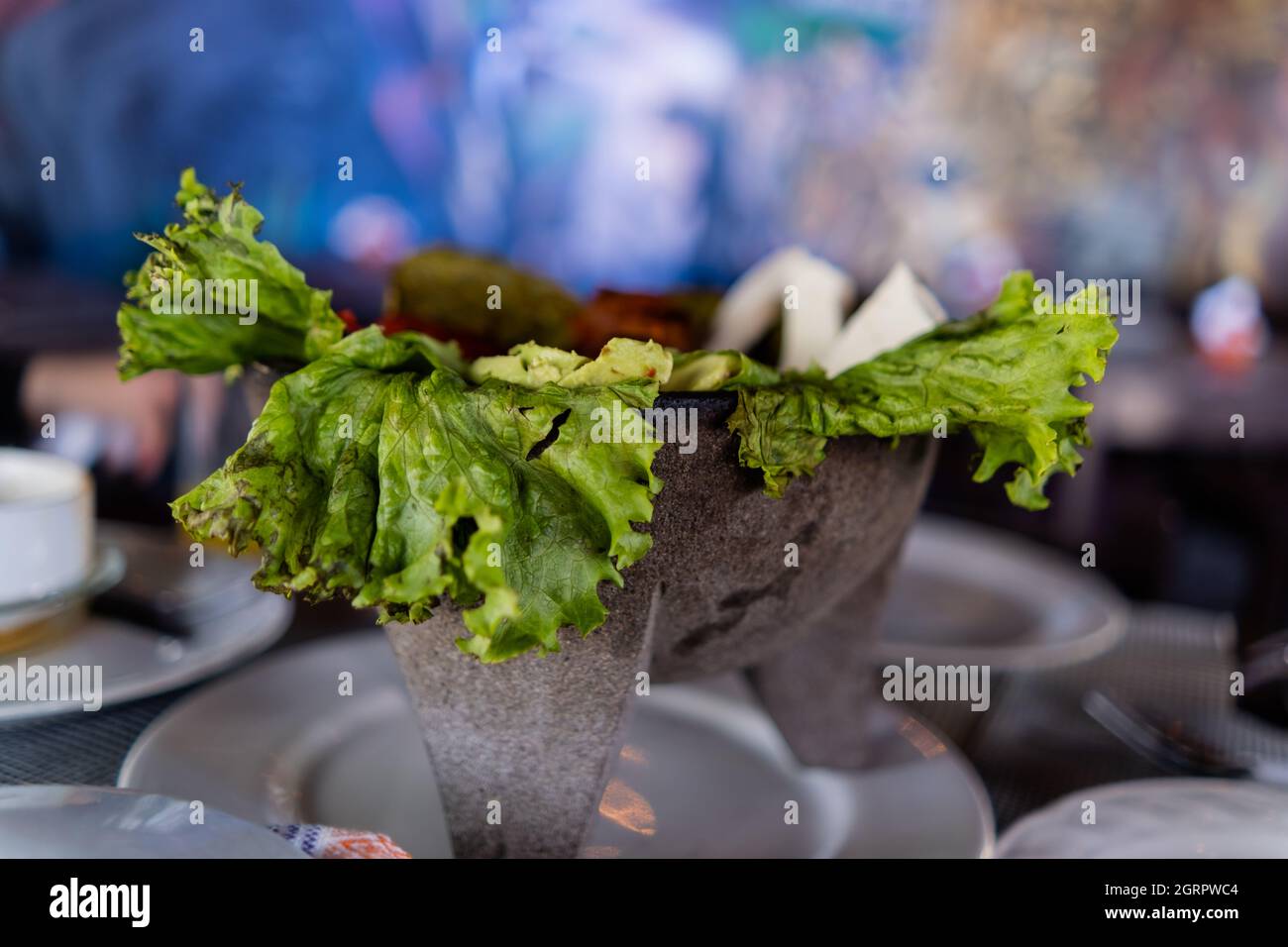 Lettuce, white cheese slices, and roasted nopales in Mexican molcajete ...