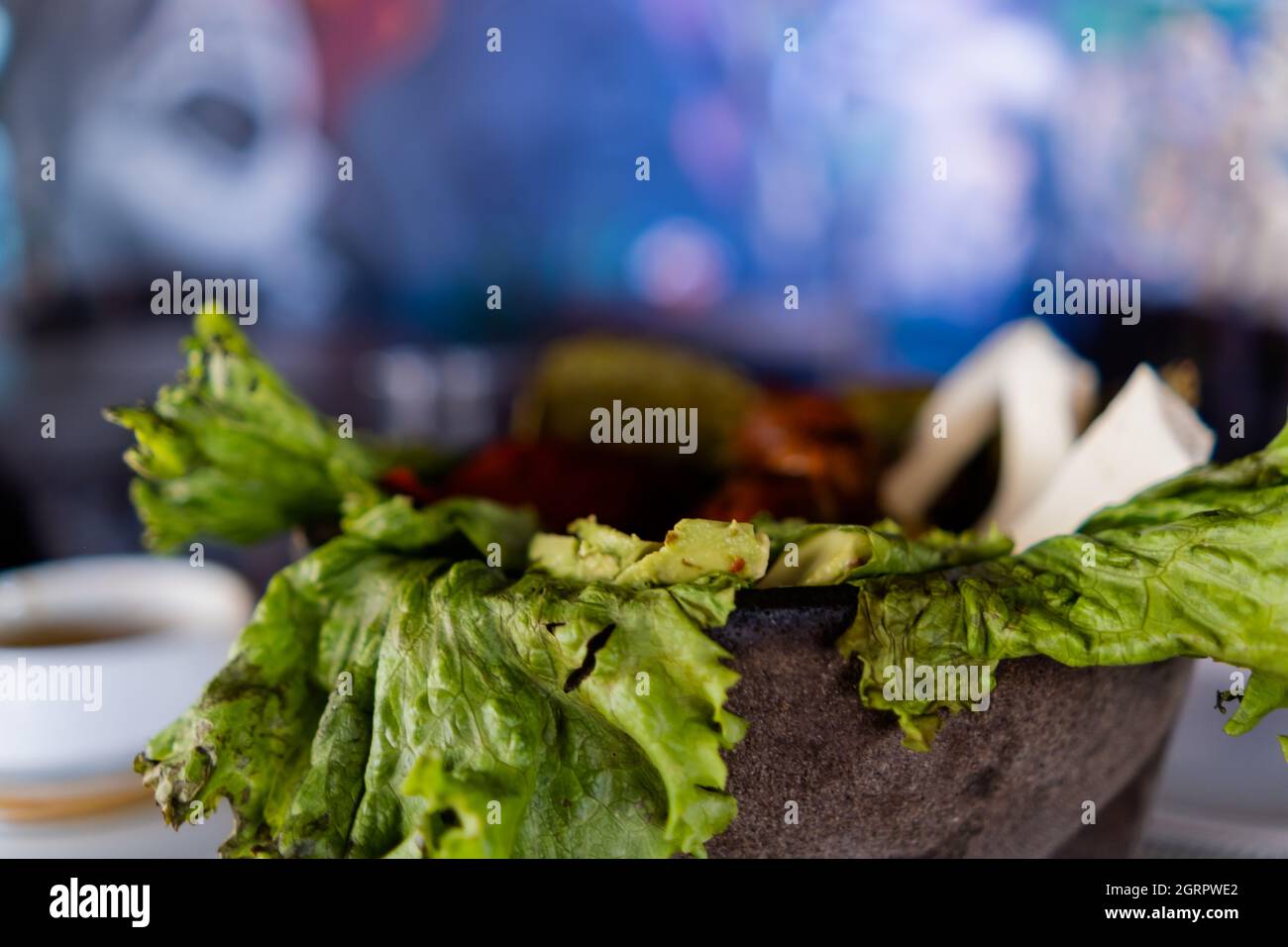 Lettuce, white cheese slices, and roasted nopales in Mexican molcajete ...