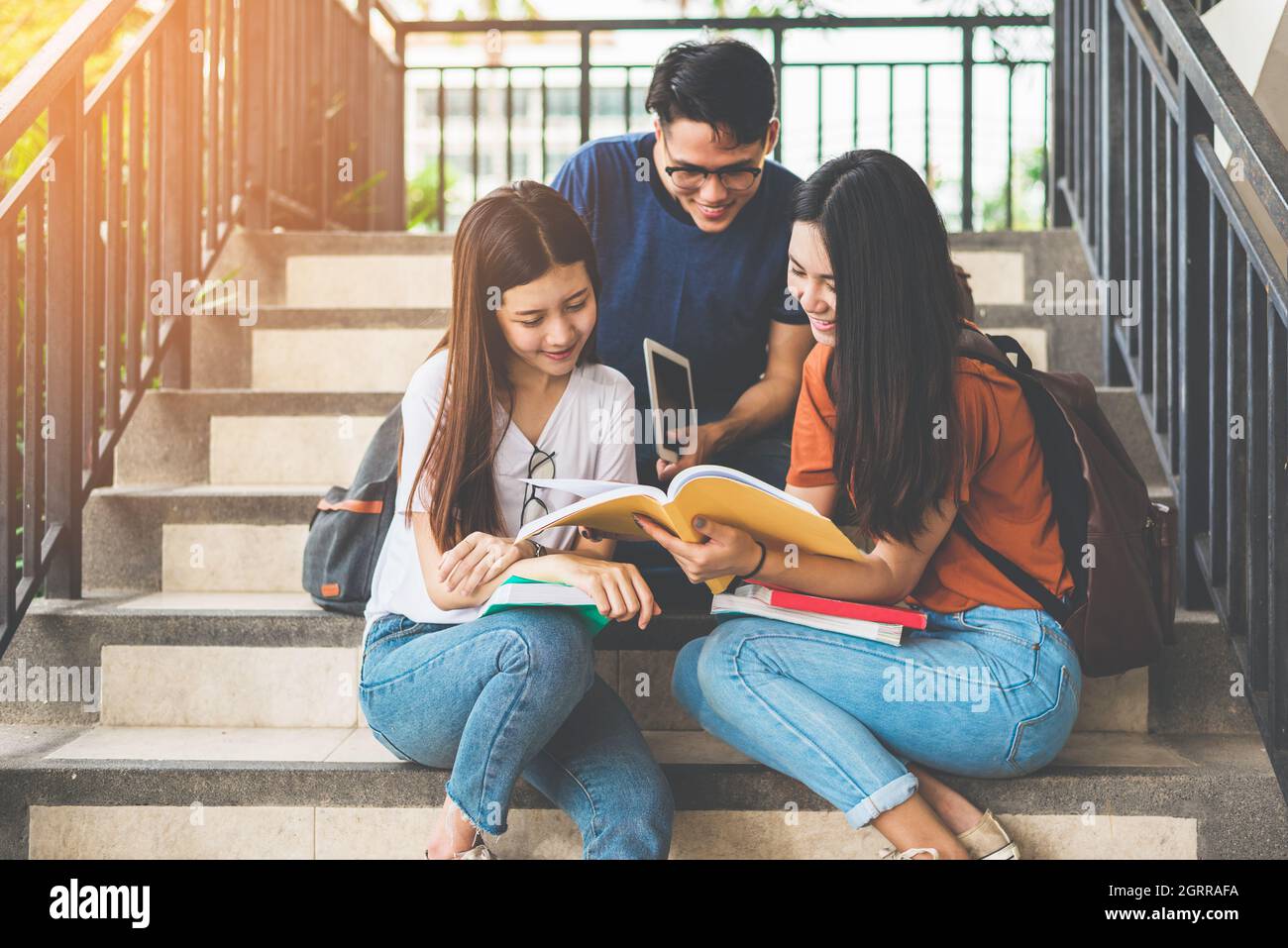 Friends Reading Book While Sitting On Staircase Stock Photo - Alamy