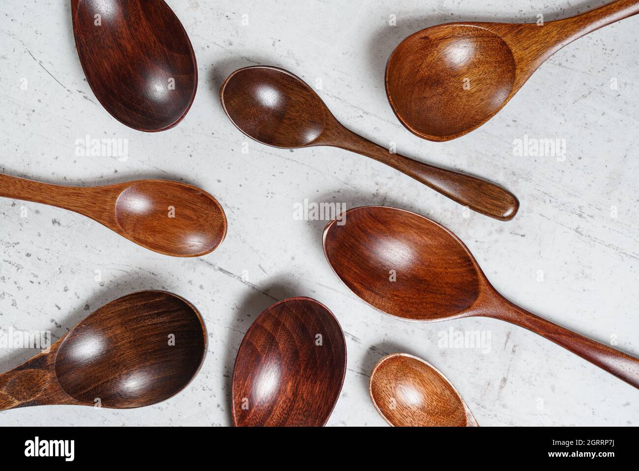Small spoons made of dark wood, on white working board, view from above ...