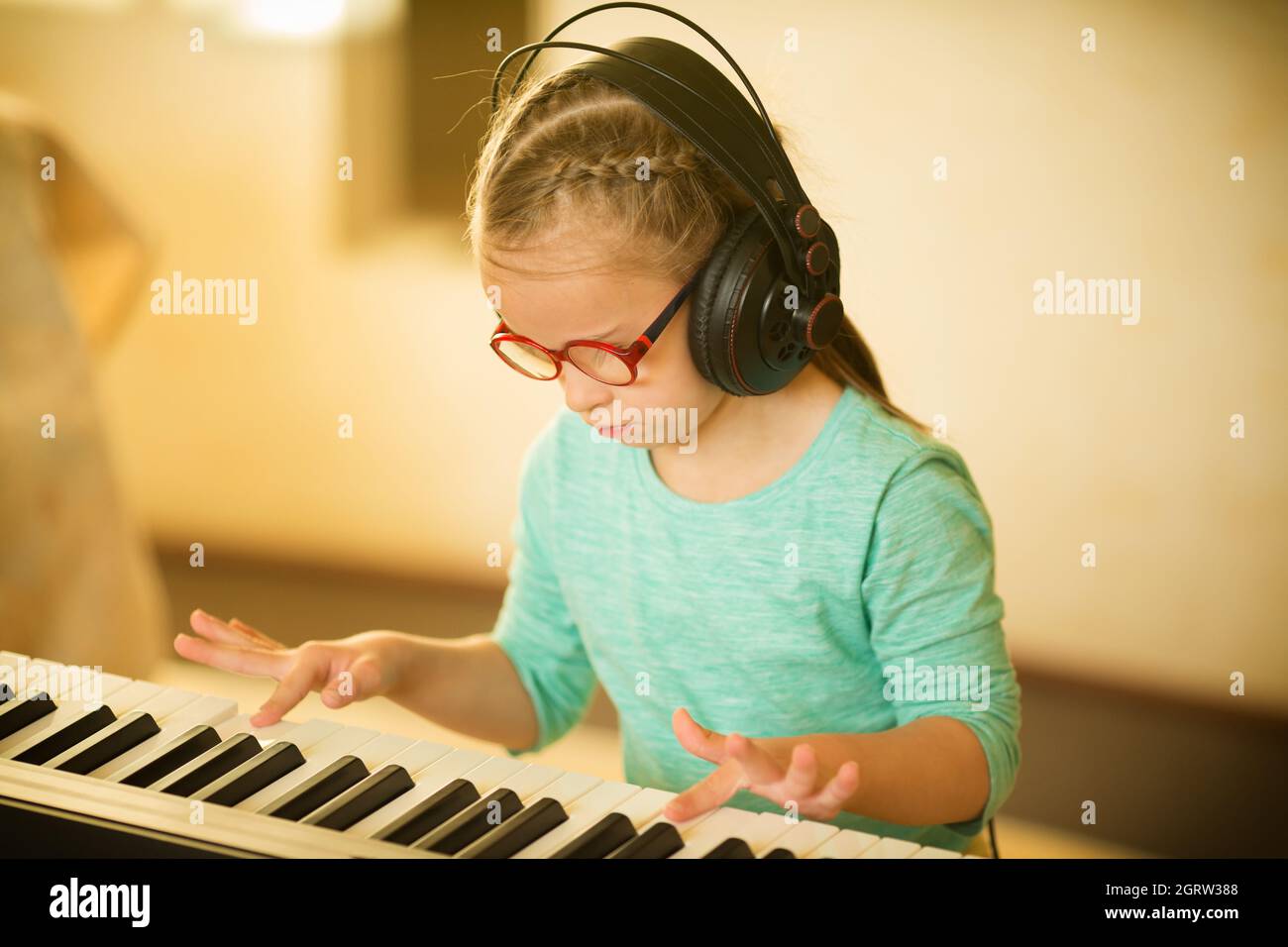 A girl with Down syndrome learns to play the piano and listens to music Stock Photo - Alamy