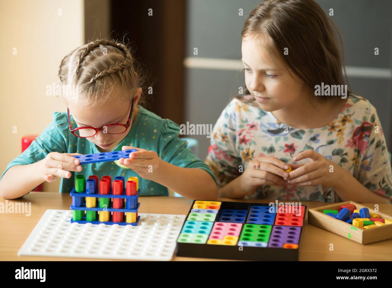 Girl with down syndrome and her older sister have fun playing board ...
