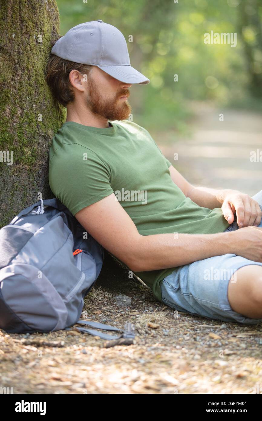 hiker with backpack sleeping against a tree in the forest Stock Photo ...