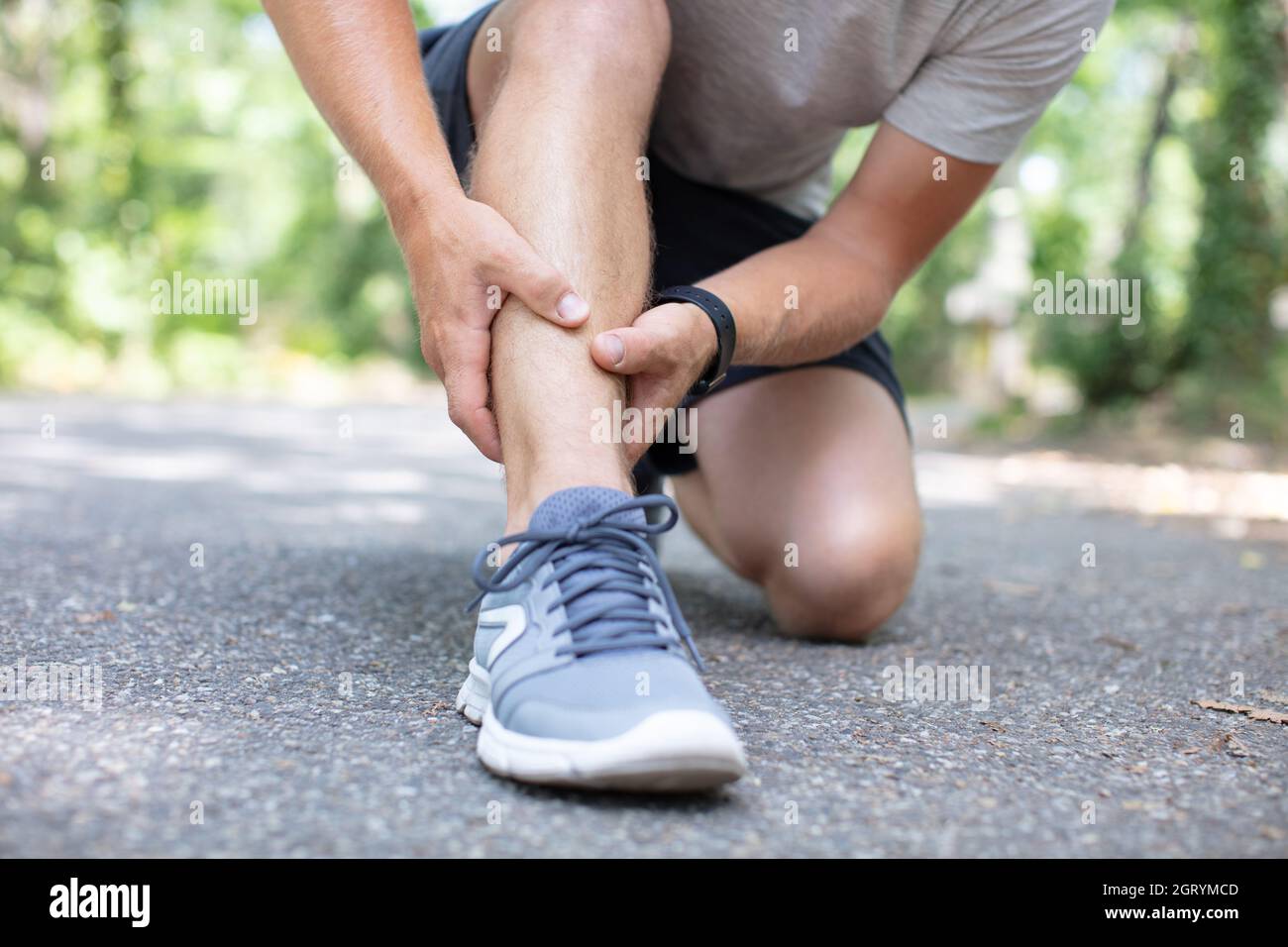 runner with leg injury sitting on floor of running track Stock Photo ...
