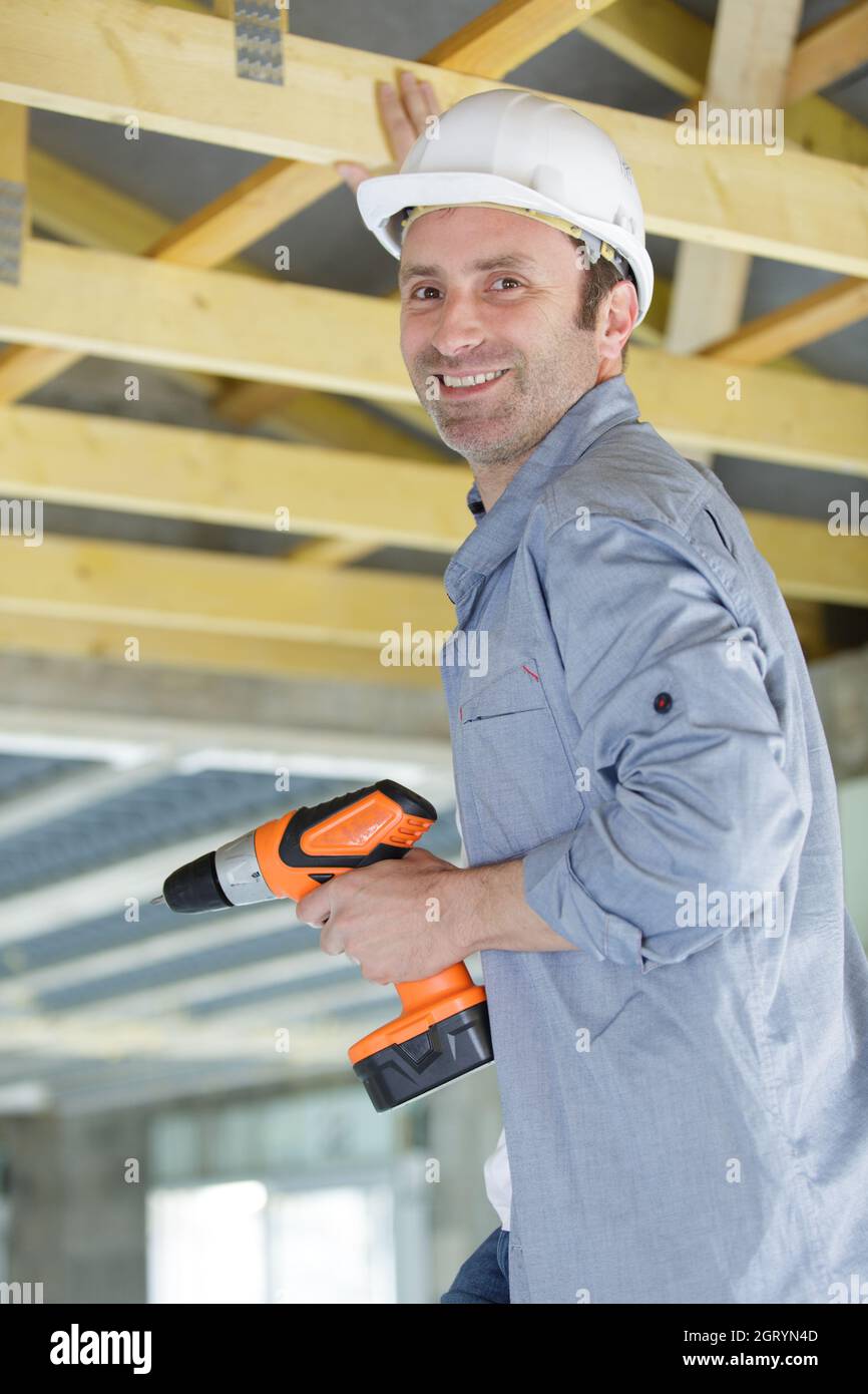mature builder twists the screw on the ceiling Stock Photo - Alamy